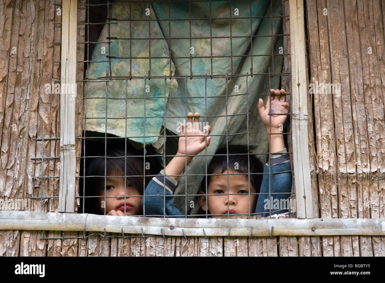 Listless Penan children looking through the window of their bamboo hut ...