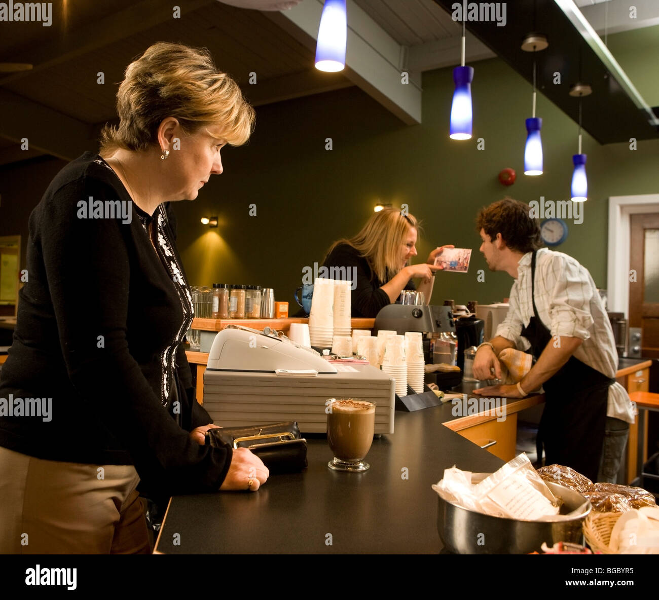 Woman waiting at counter while barista talks Stock Photo - Alamy