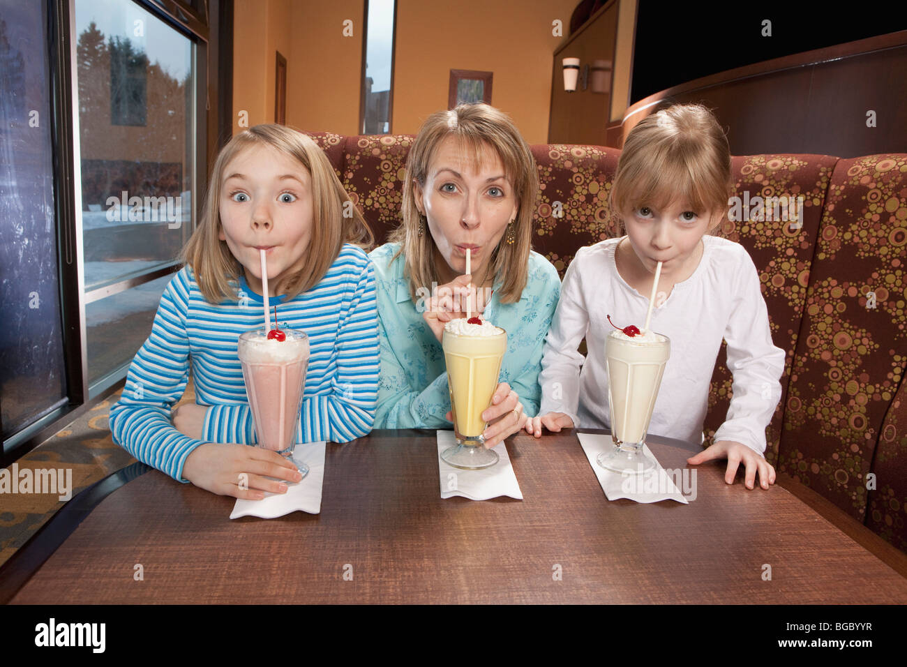 Mother and daughters sharing milkshakes Stock Photo - Alamy