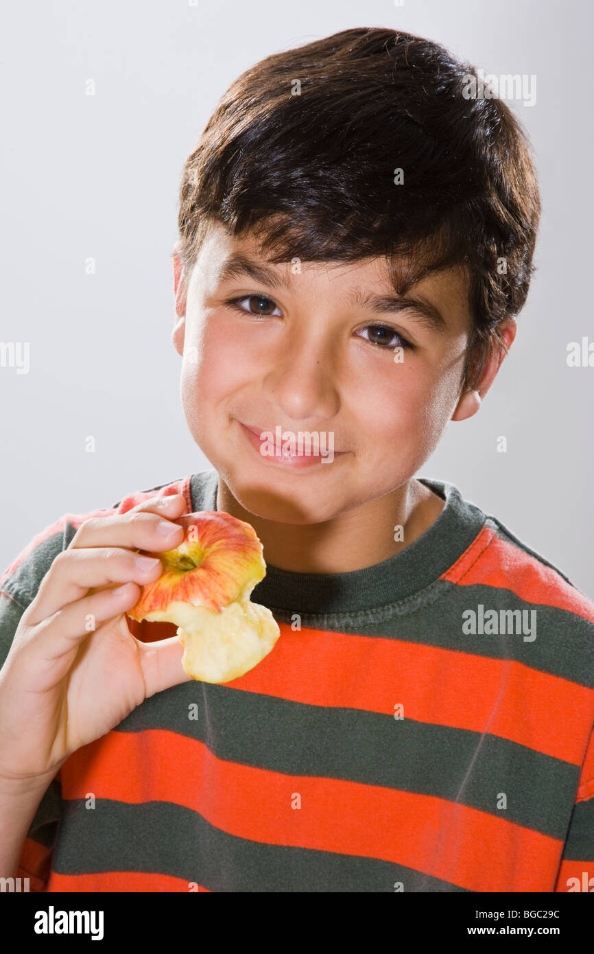 Boy eating an apple, studio, smiling, portrait Stock Photo - Alamy