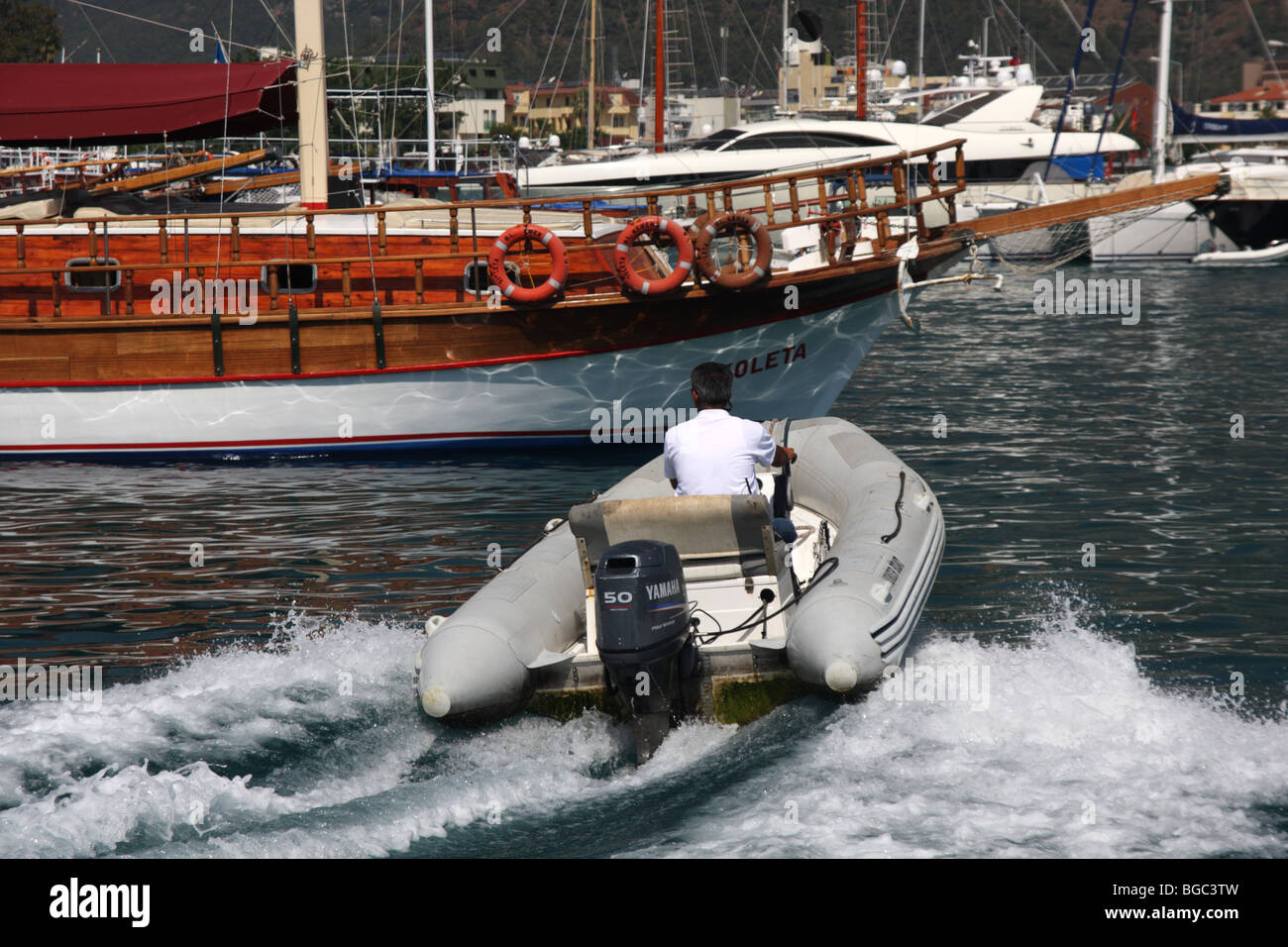 The boat with one man in the port float next to yachts. Mediterranean ...