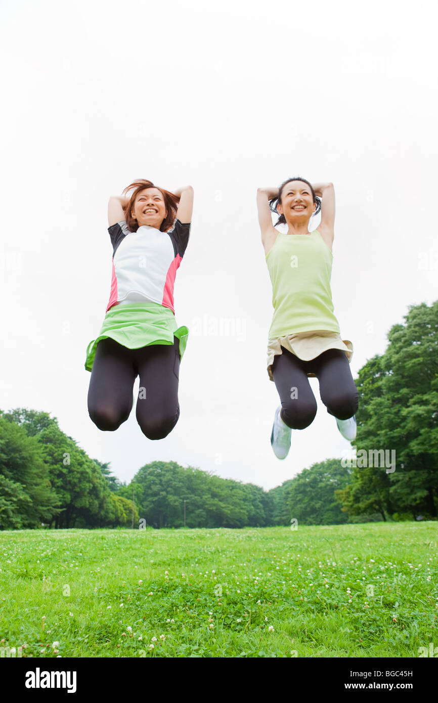 Mid adult woman and young woman jumping Stock Photo - Alamy