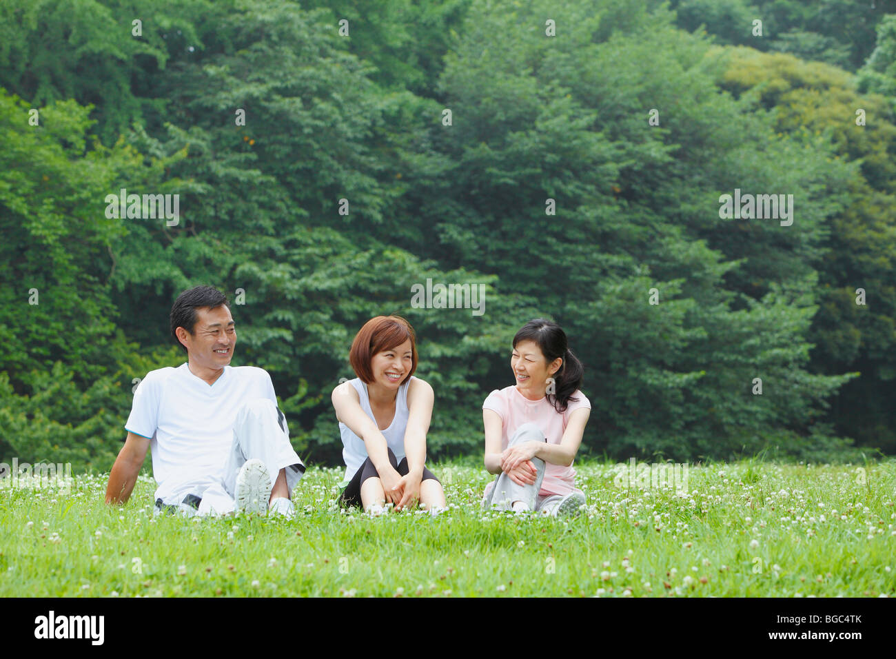 Three people sitting on grass Stock Photo - Alamy