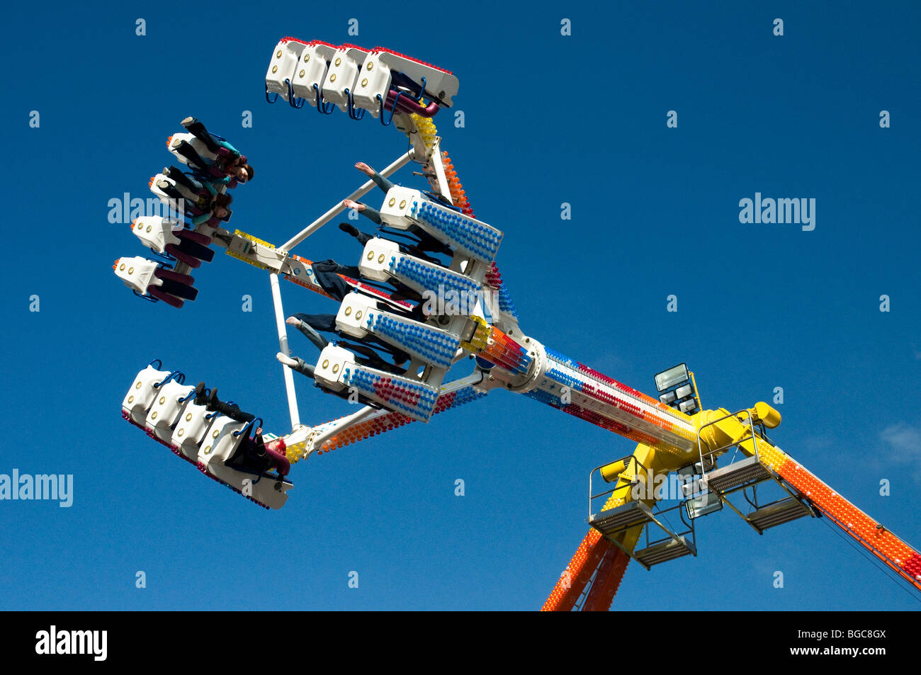 Freak Out fairground ride during pendulum swing , against blue sky ...