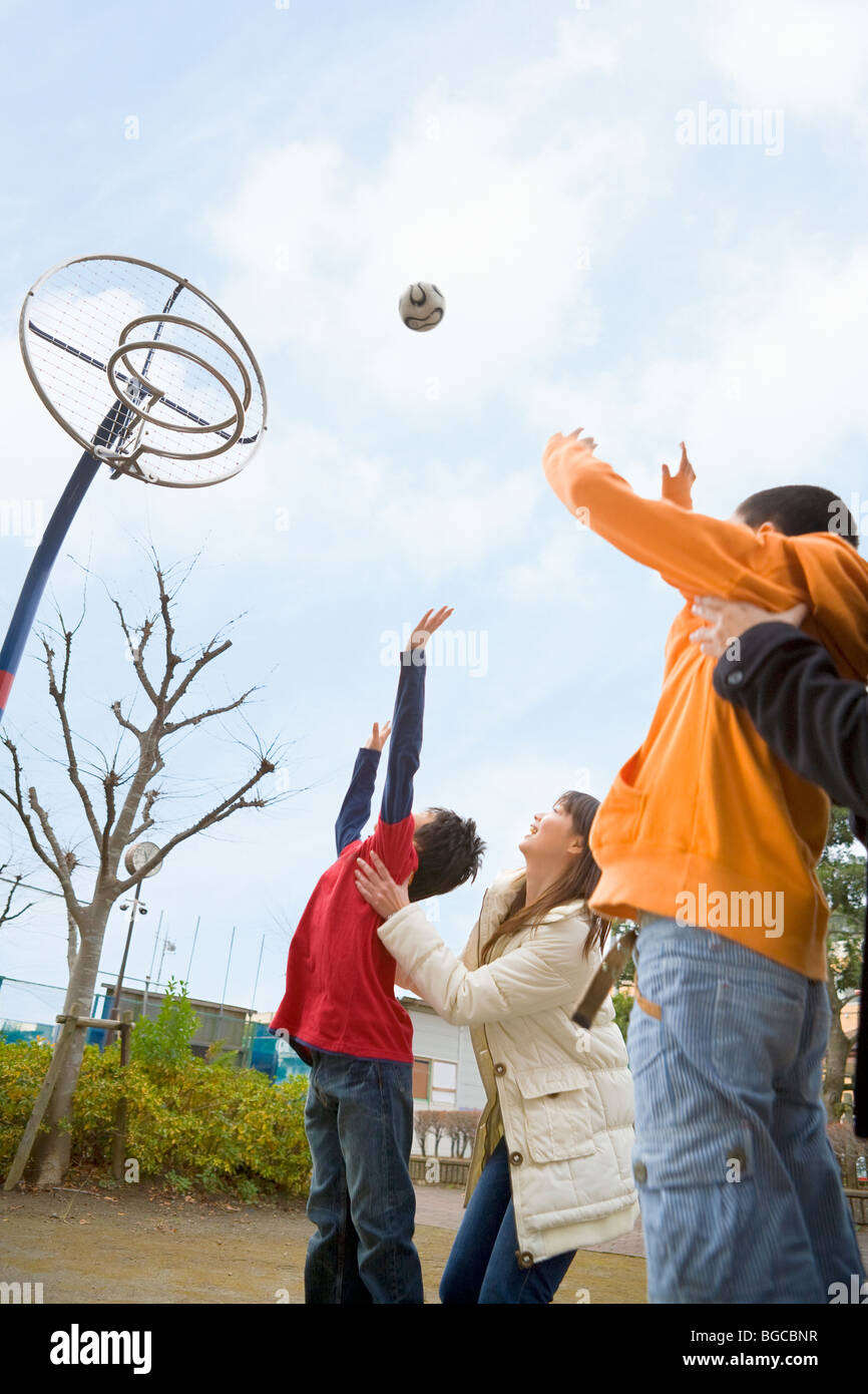 Two boys throwing ball with mothers Stock Photo - Alamy