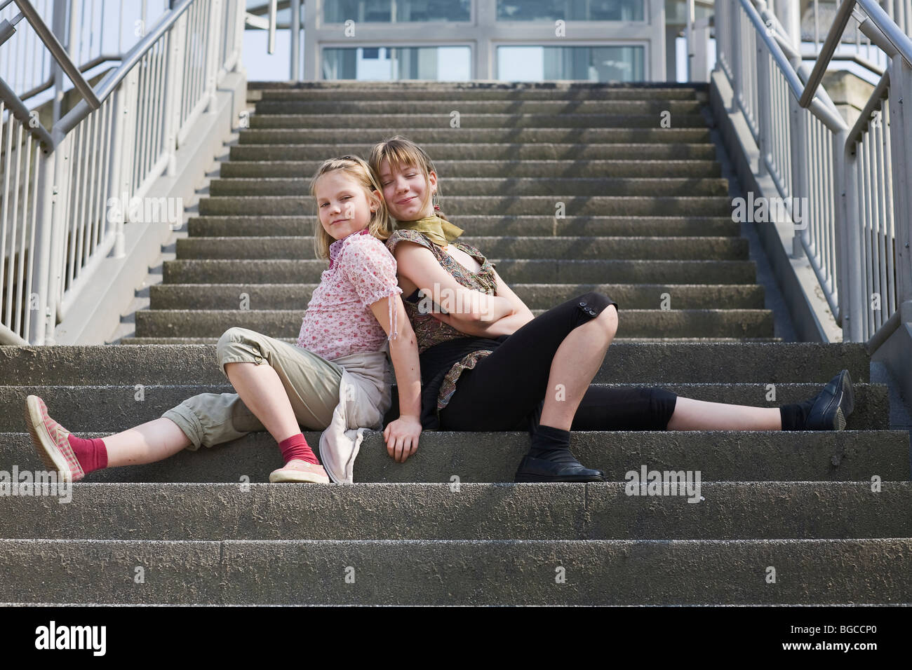 Two young sisters sitting on steps Stock Photo - Alamy