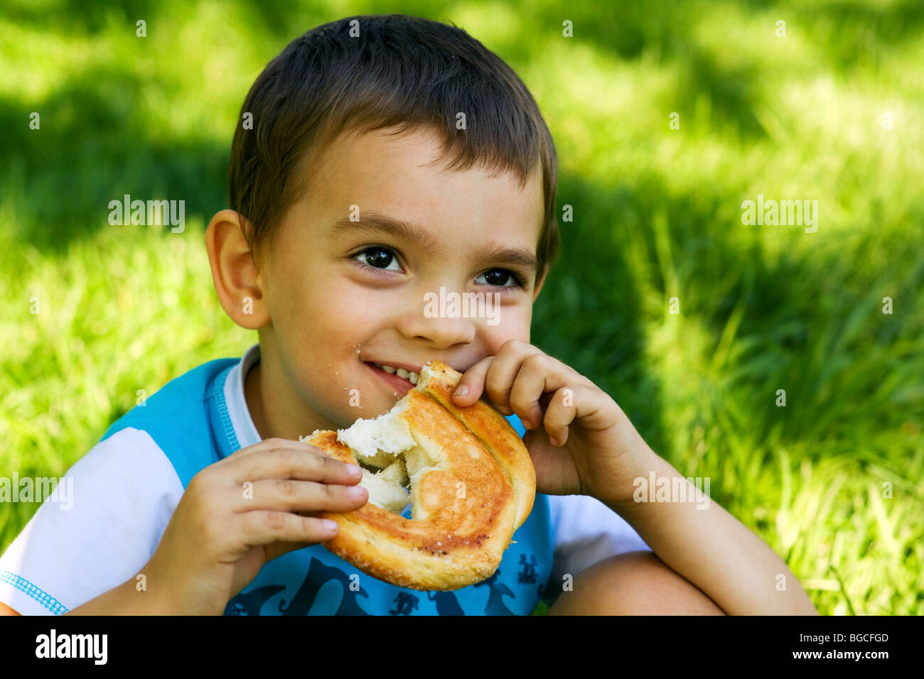 Little boy eating a sweet bun on nature Stock Photo - Alamy
