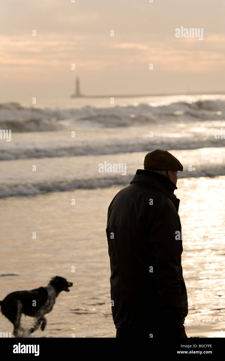A man walks along the beach on a cold but sunny winter's day Stock ...