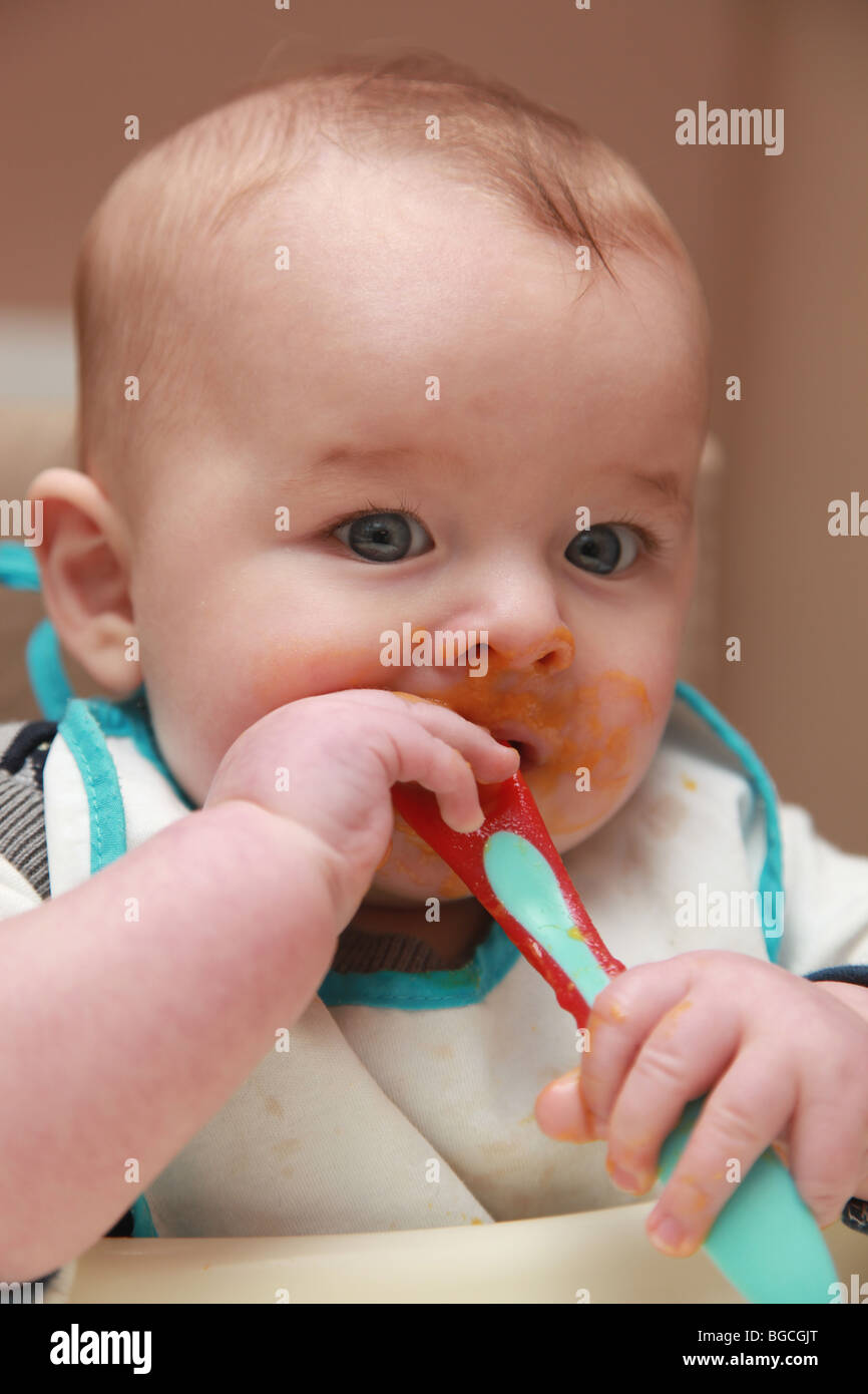 Baby boy feeding himself Stock Photo - Alamy
