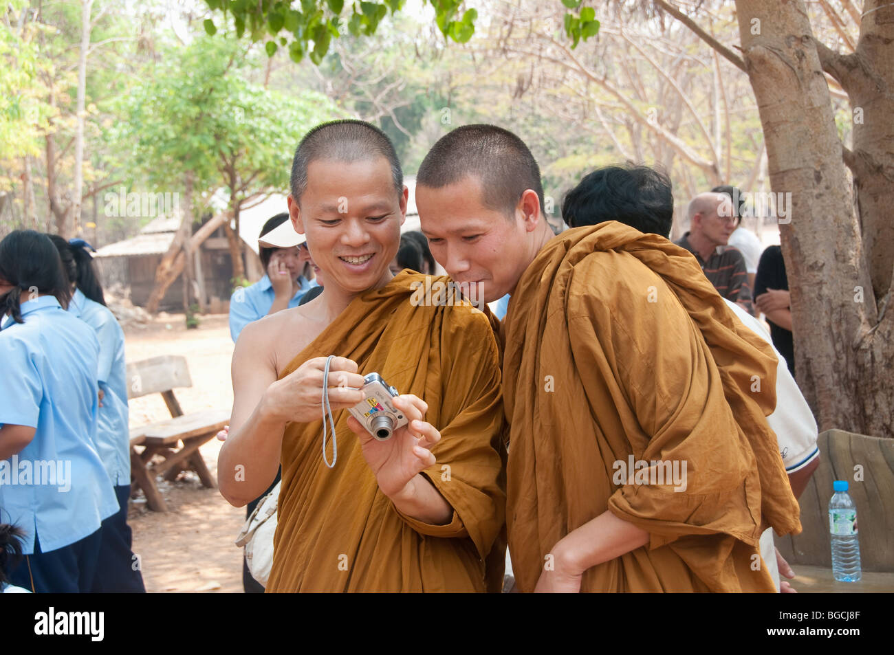 two Buddhist monks look at their photos of tiger temple in Kanchanaburi ...