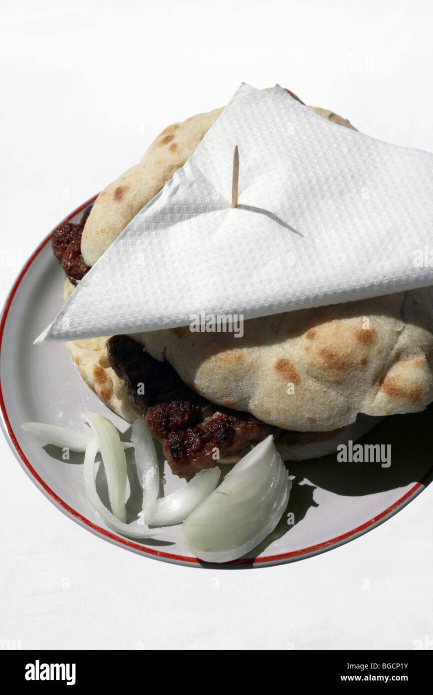 Cevapcici in bread with sliced onion served on a plate. Bosnia, Bosnian ...