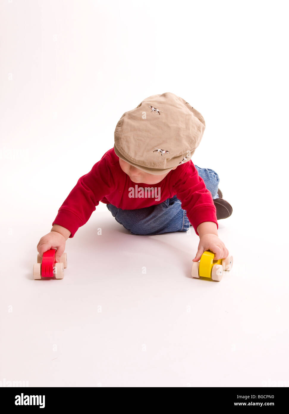 1 year old little boy wearing big cap plays with toy cars isolated on ...