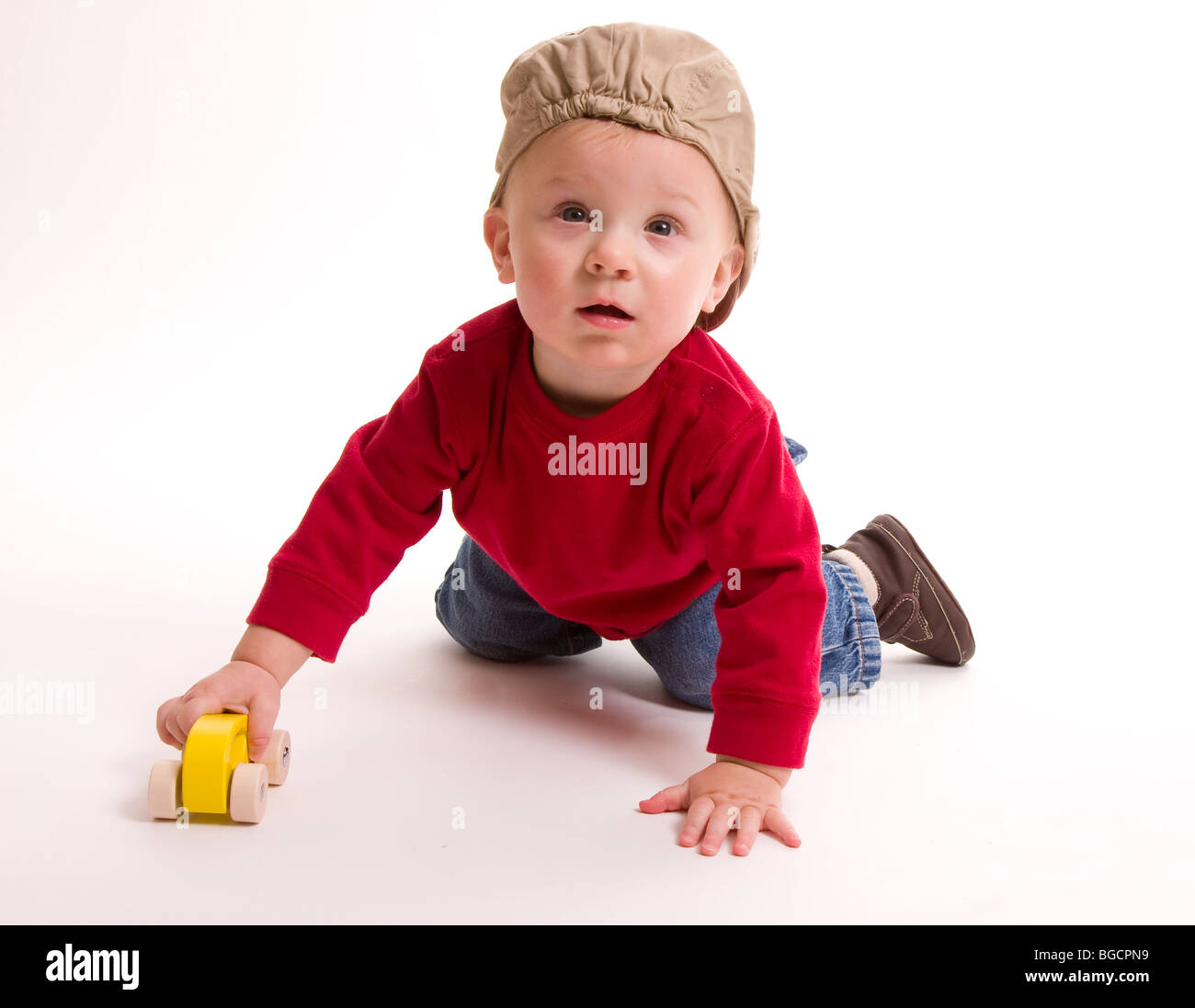 1 year old little boy wearing big cap backwards plays with toy car ...