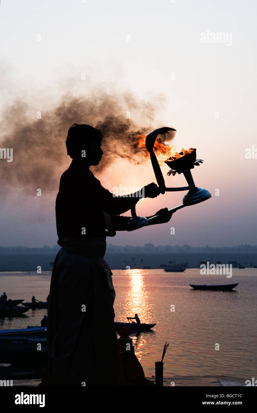 Hindu priest worshipping sun god Surya at sunrise on the bank of Ganges ...