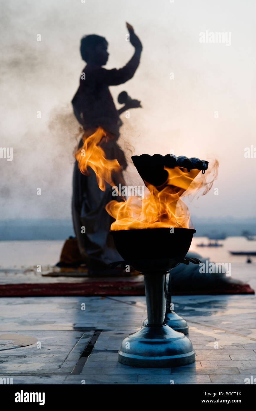 Hindu priest worshipping sun god Surya at sunrise on the bank of Ganges ...