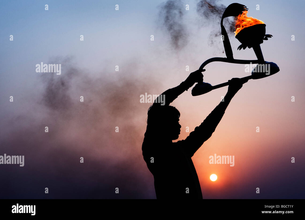 Hindu priest worshipping sun god Surya at sunrise on the bank of Ganges ...
