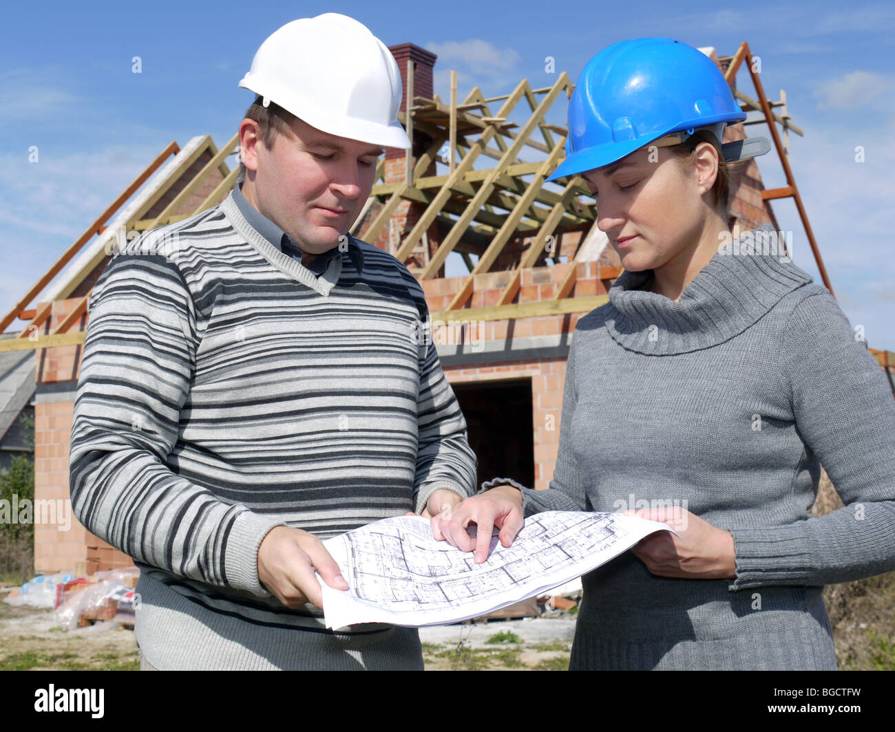 Female and male building engineers studying building plans over ...