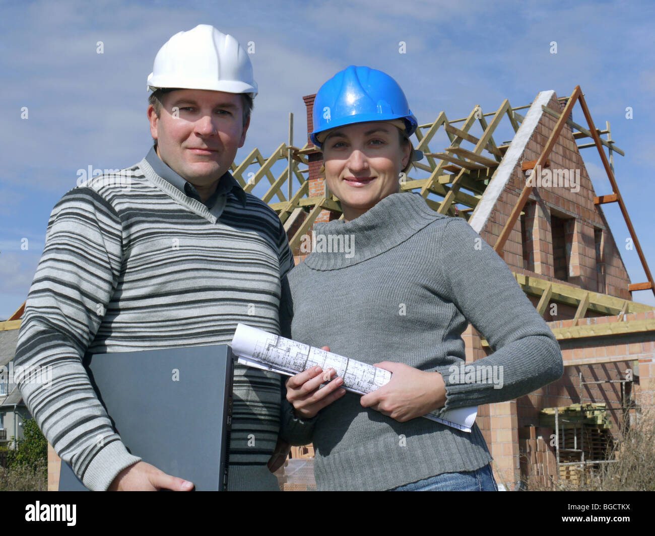 Female and male building engineers wearing helmets posing with building ...