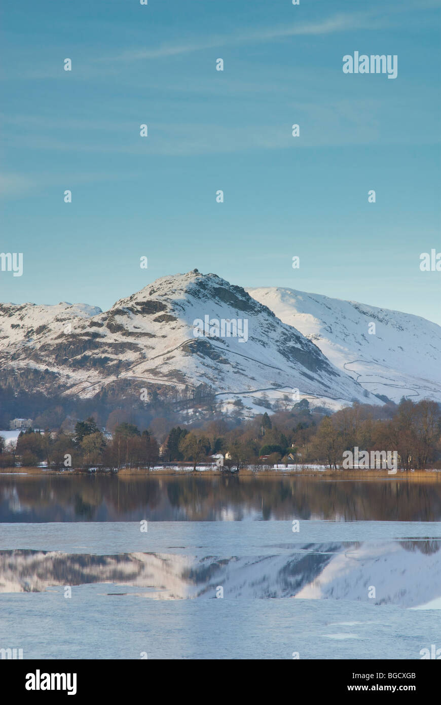 Helm Crag reflected in the icy water of Grasmere, Lake District ...