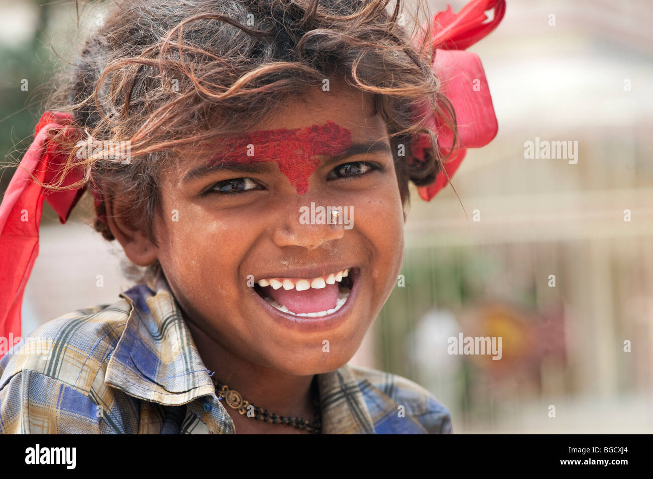 Very poor pretty Indian gypsy girl smiling with red ribbons in her hair ...