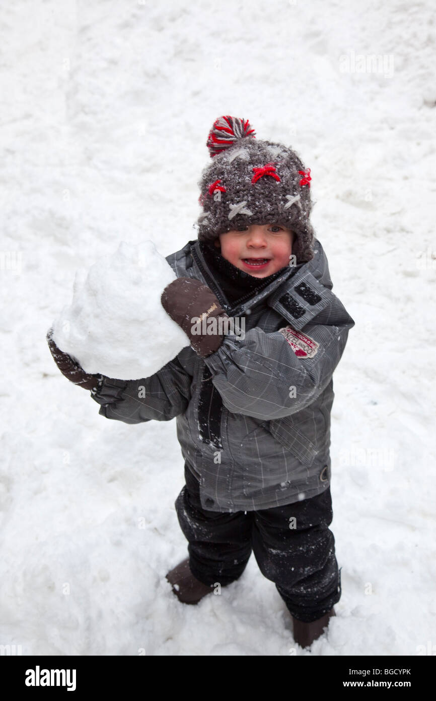 Small boy making a large snowball for a snowman in Old Quebec City ...