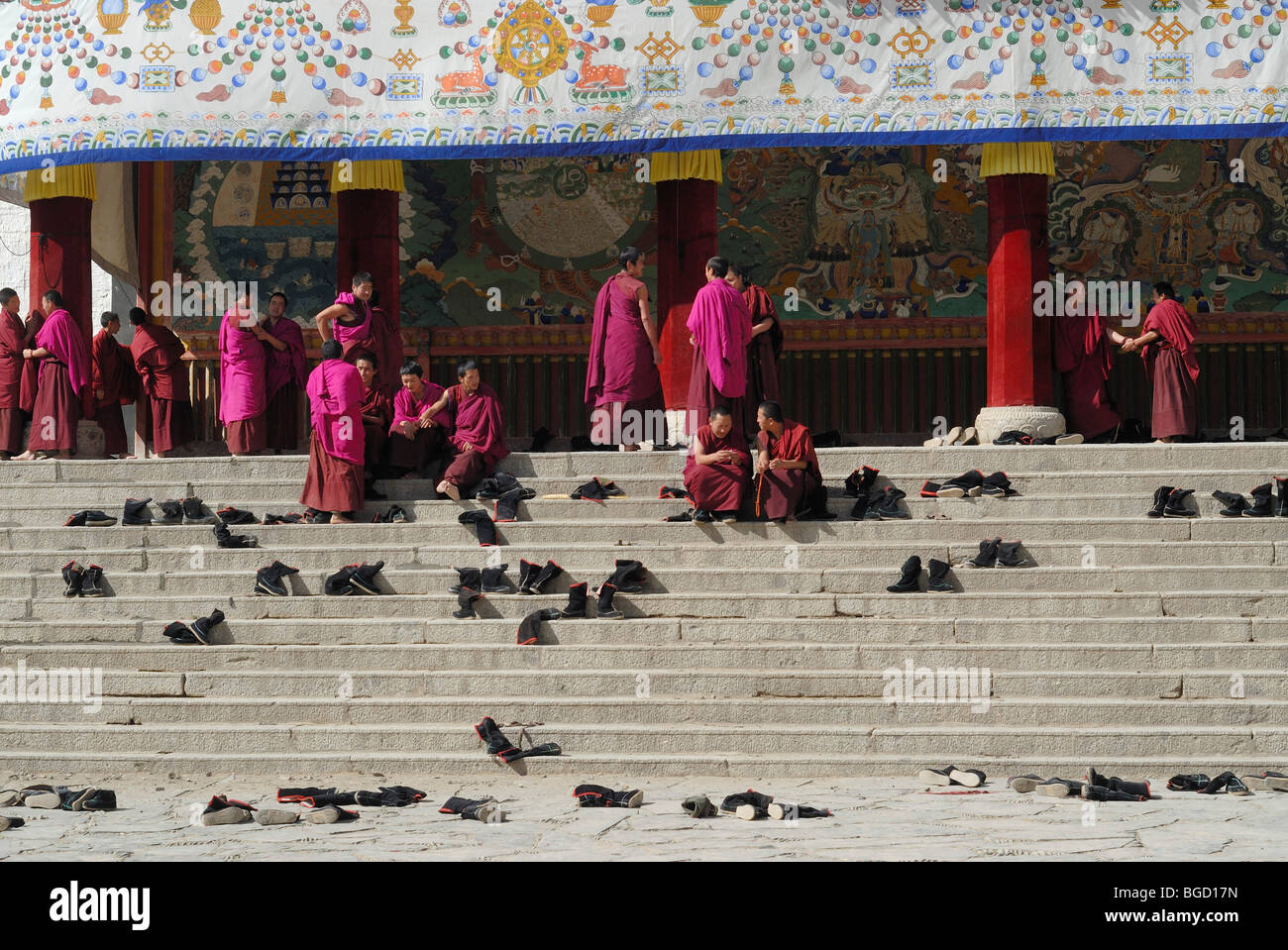 Tibetan monks in cowls of the Gelukpa order sitting on the stairs of ...