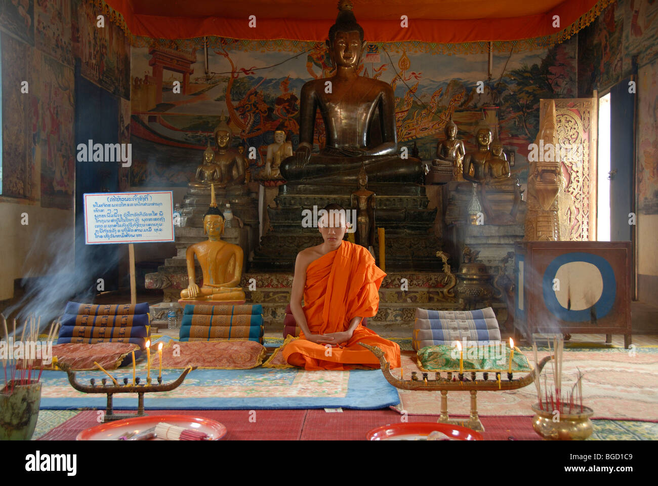Theravada Buddhism, a monk in a temple, ancient Buddha statue in bronze ...