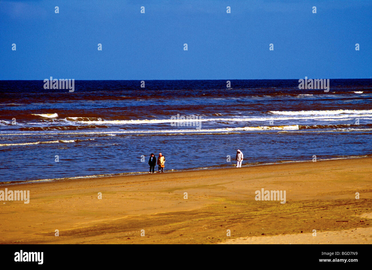 People walking along beach on a chilly spring morning at Noordwijk an ...
