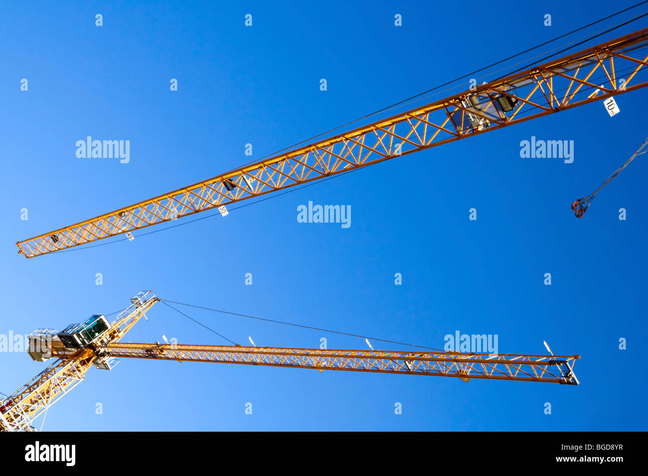 Two construction cranes against a blue sky Stock Photo - Alamy