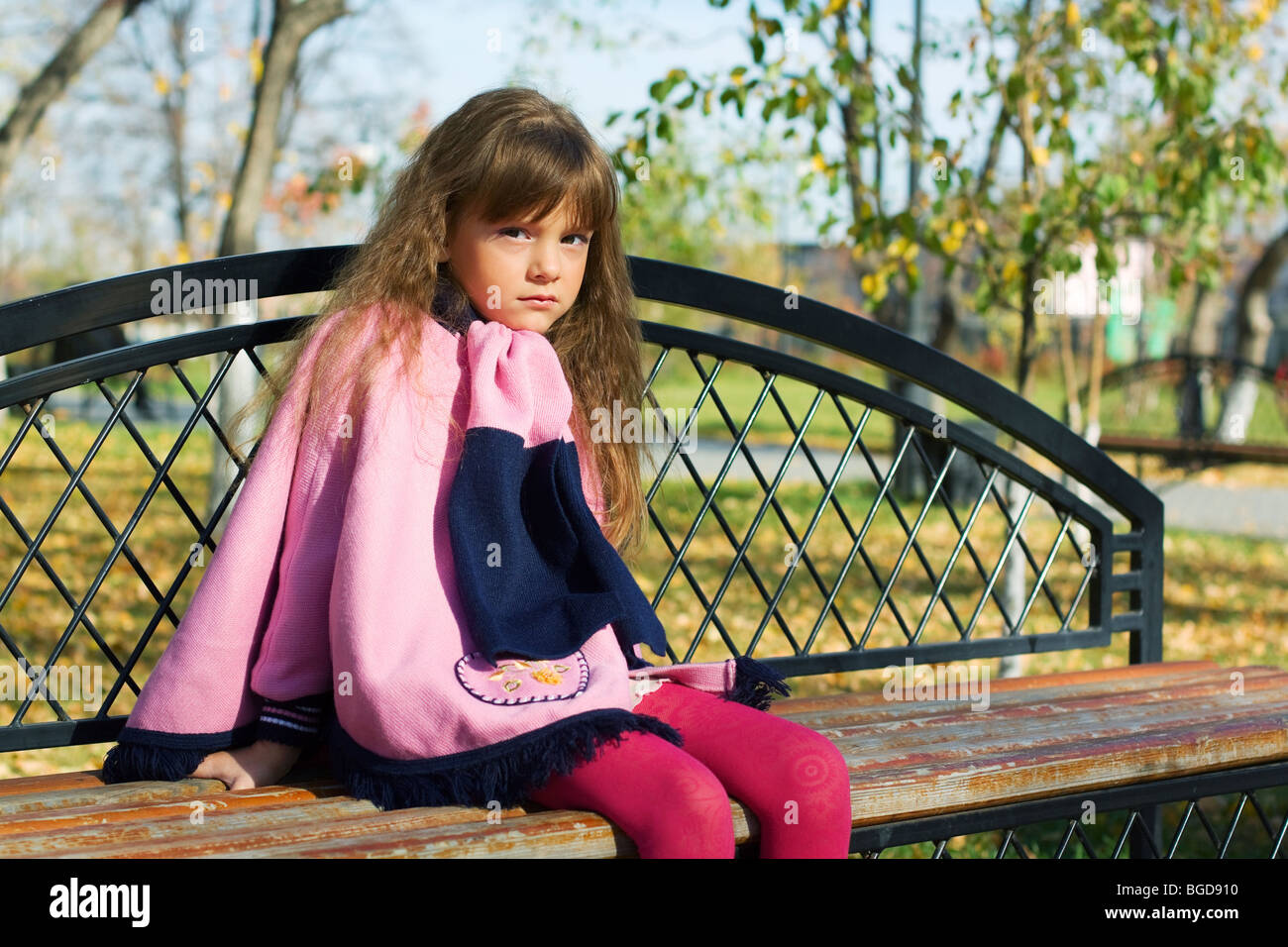 Thoughtful little girl sitting on a bench in the park Stock Photo - Alamy