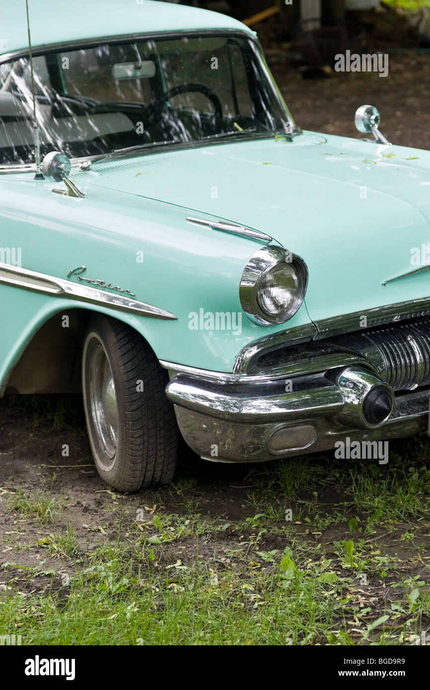 The front of a light blue classic Pontiac, focus on the headlight and ...
