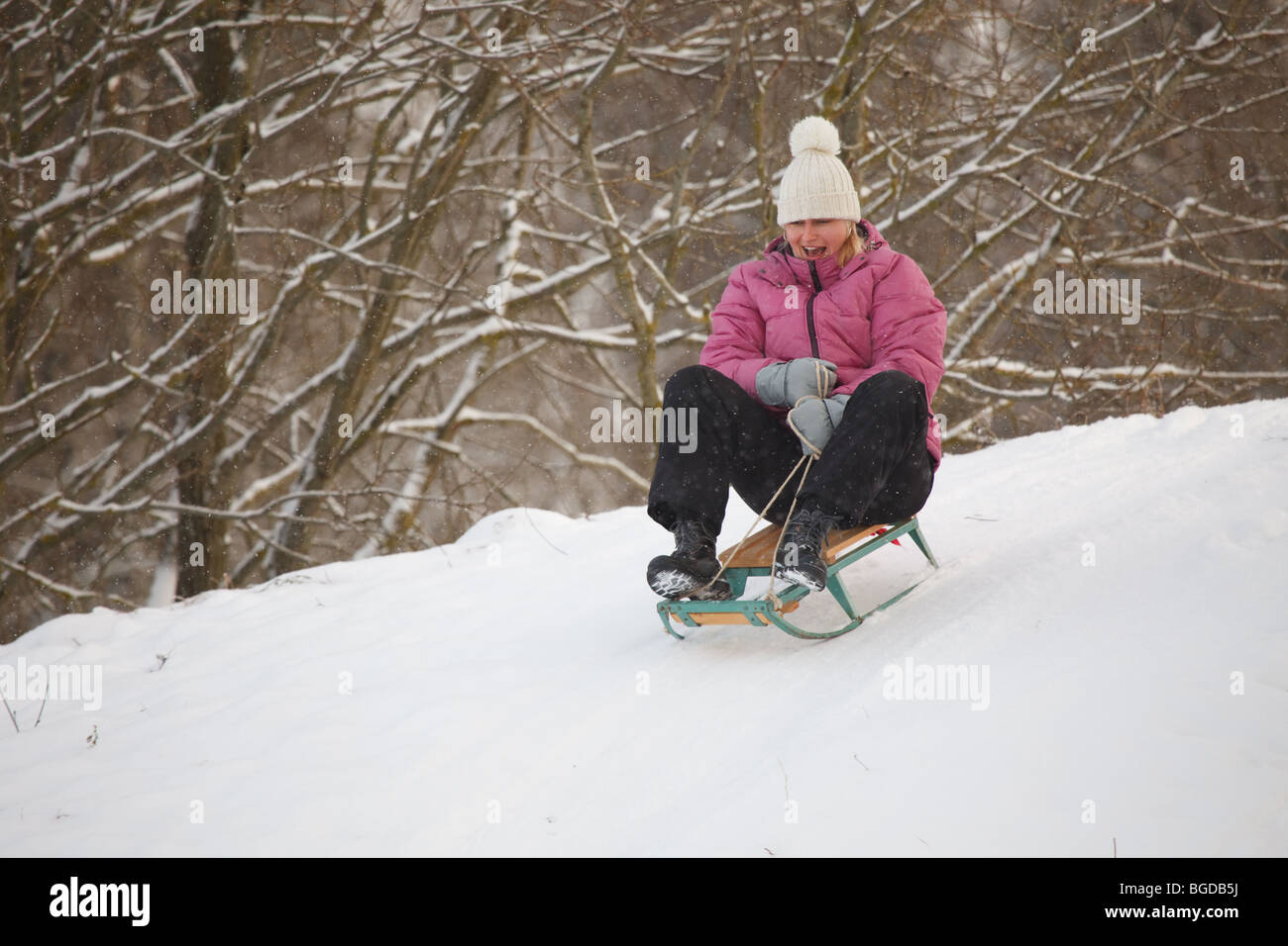 Girl sledging down hill, bright and joyful winter scene Stock Photo - Alamy