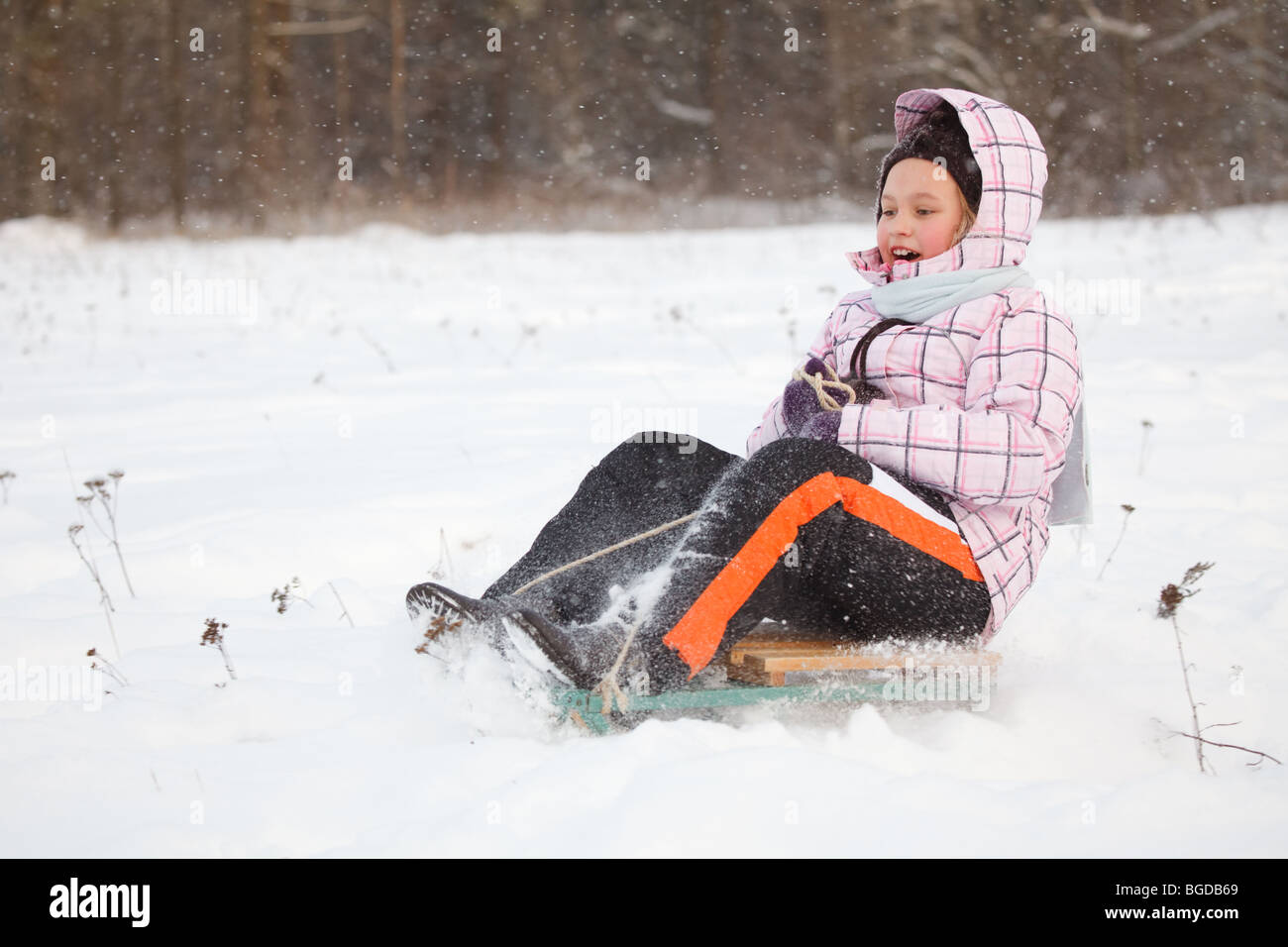 Little girl sledging down hill, bright and joyful winter scene Stock ...