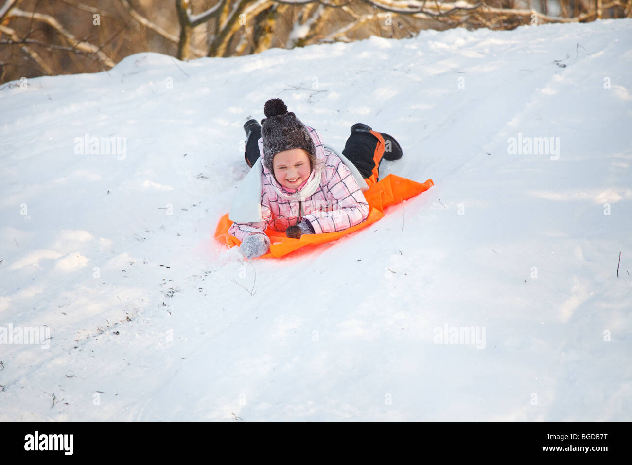 Little girl sledging down hill, bright and joyful winter scene Stock ...