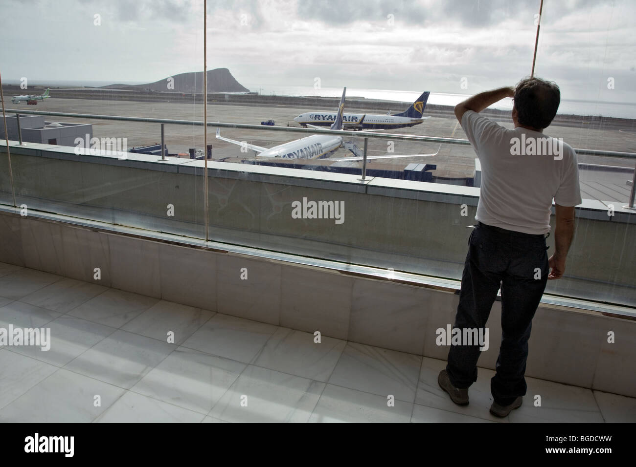 a man watching the runway with ryanair planes at tenerife sur airport ...