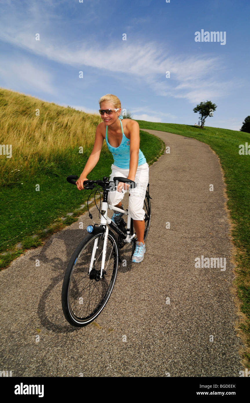 Young woman riding a bicycle, Olympic Park, Munich, Bavaria, Germany ...