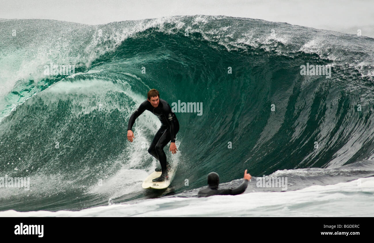 A surfer inside a big blue green wave surfing in the United Kingdom at ...