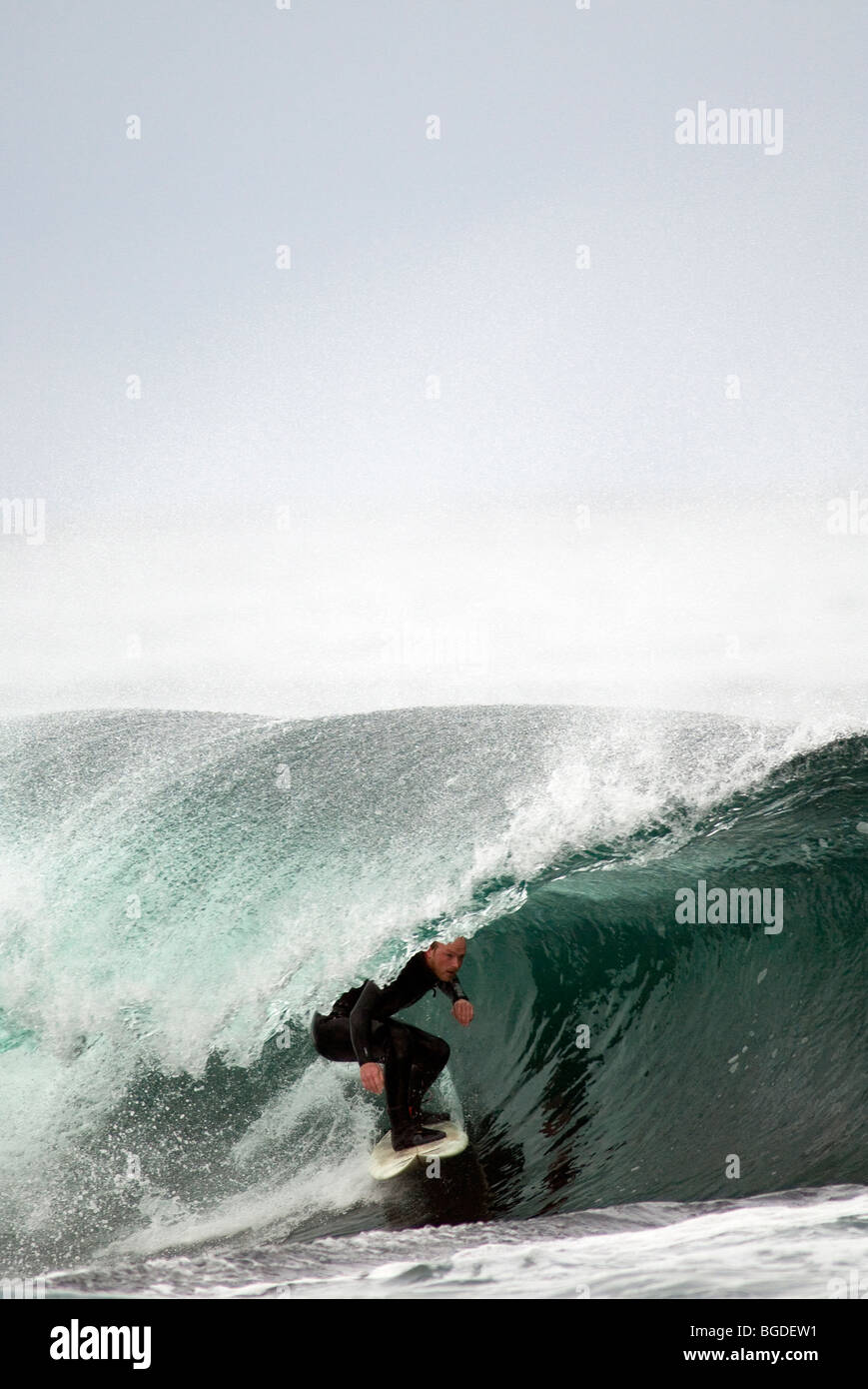 A surfer inside a big blue green wave surfing in the United Kingdom at ...