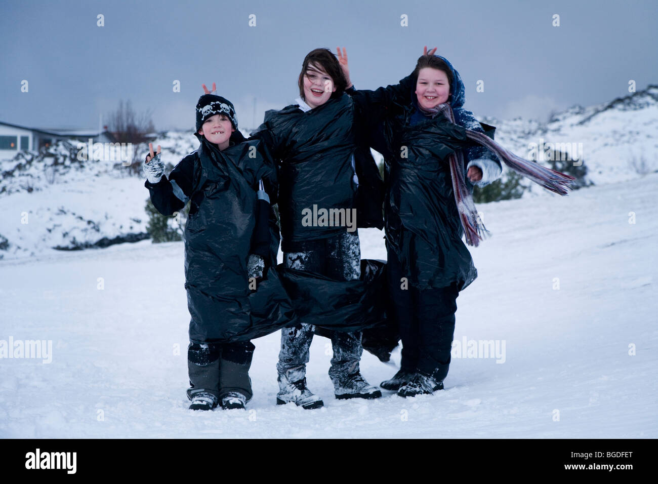 Three boys posing for camera in snow, showing victory sign ...