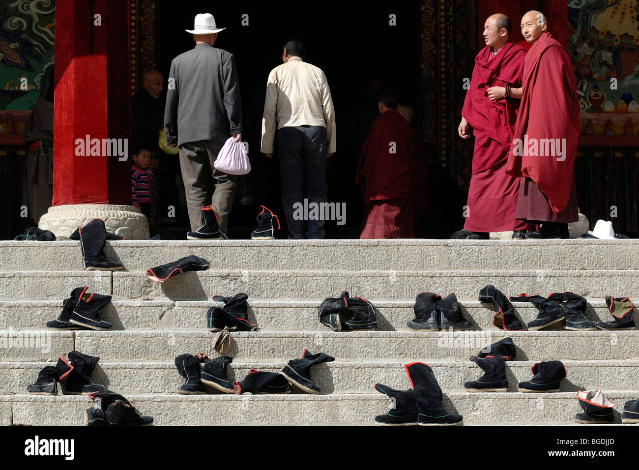 Tibetan monks in the robes of the Gelukpa order standing on the stairs ...