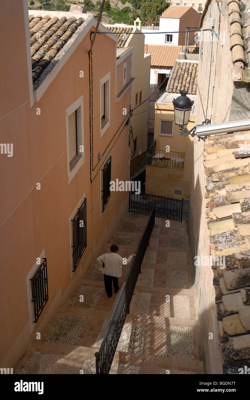woman walking down steep, narrow street in the mountain village of ...