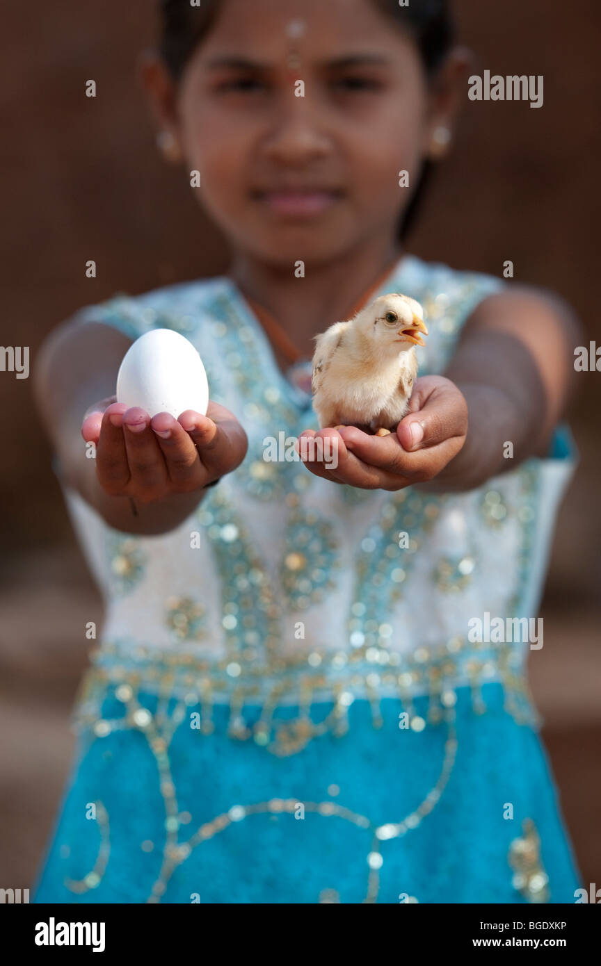 Young indian girl with baby chicken and an egg in the palm of her hands ...