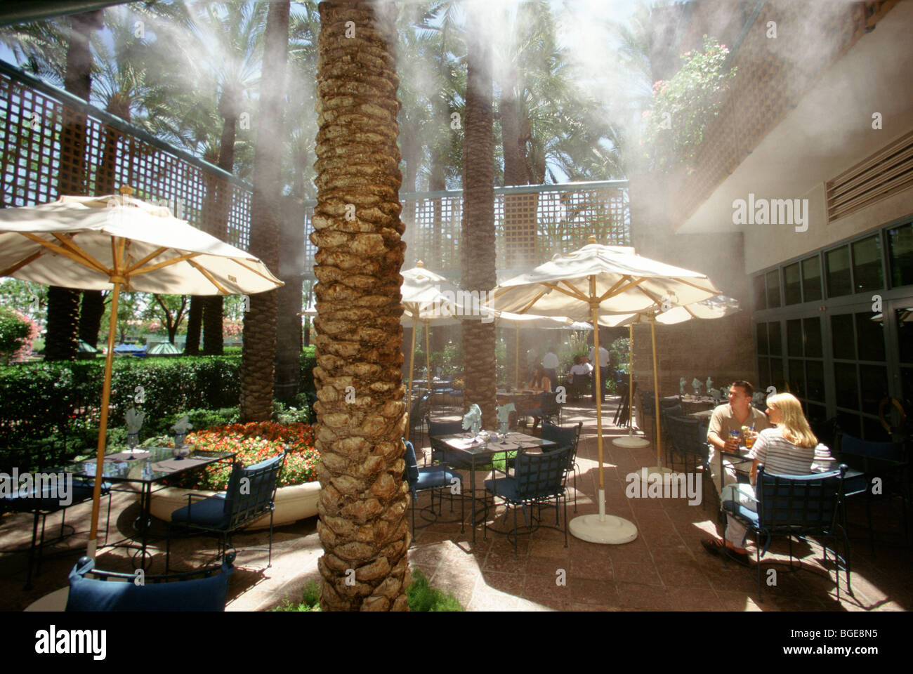 A couple sit in the outdoor restaurant of a five star hotel, kept cool ...
