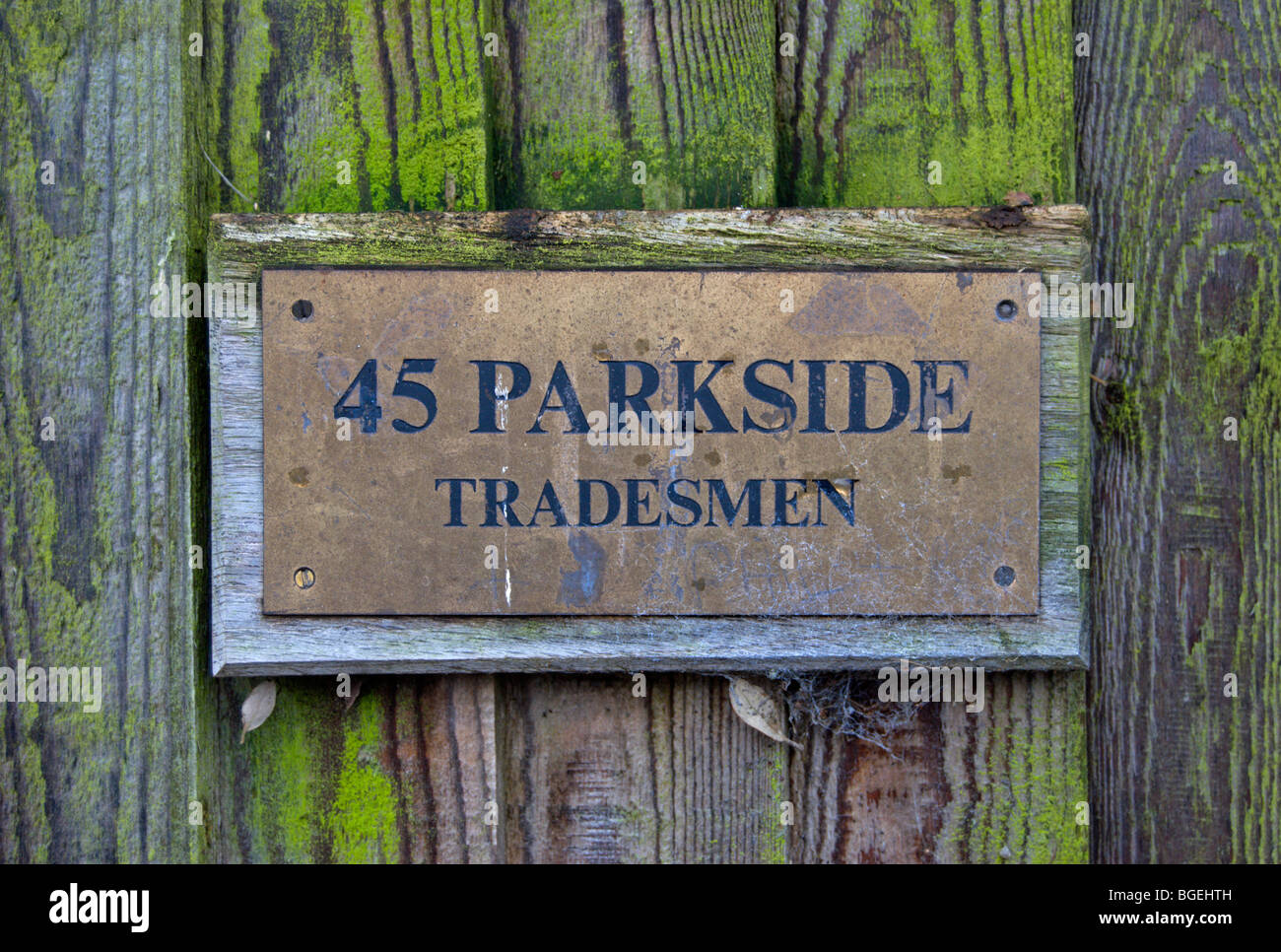 sign on wooden gate marking entrance for tradesmen at the back of a ...