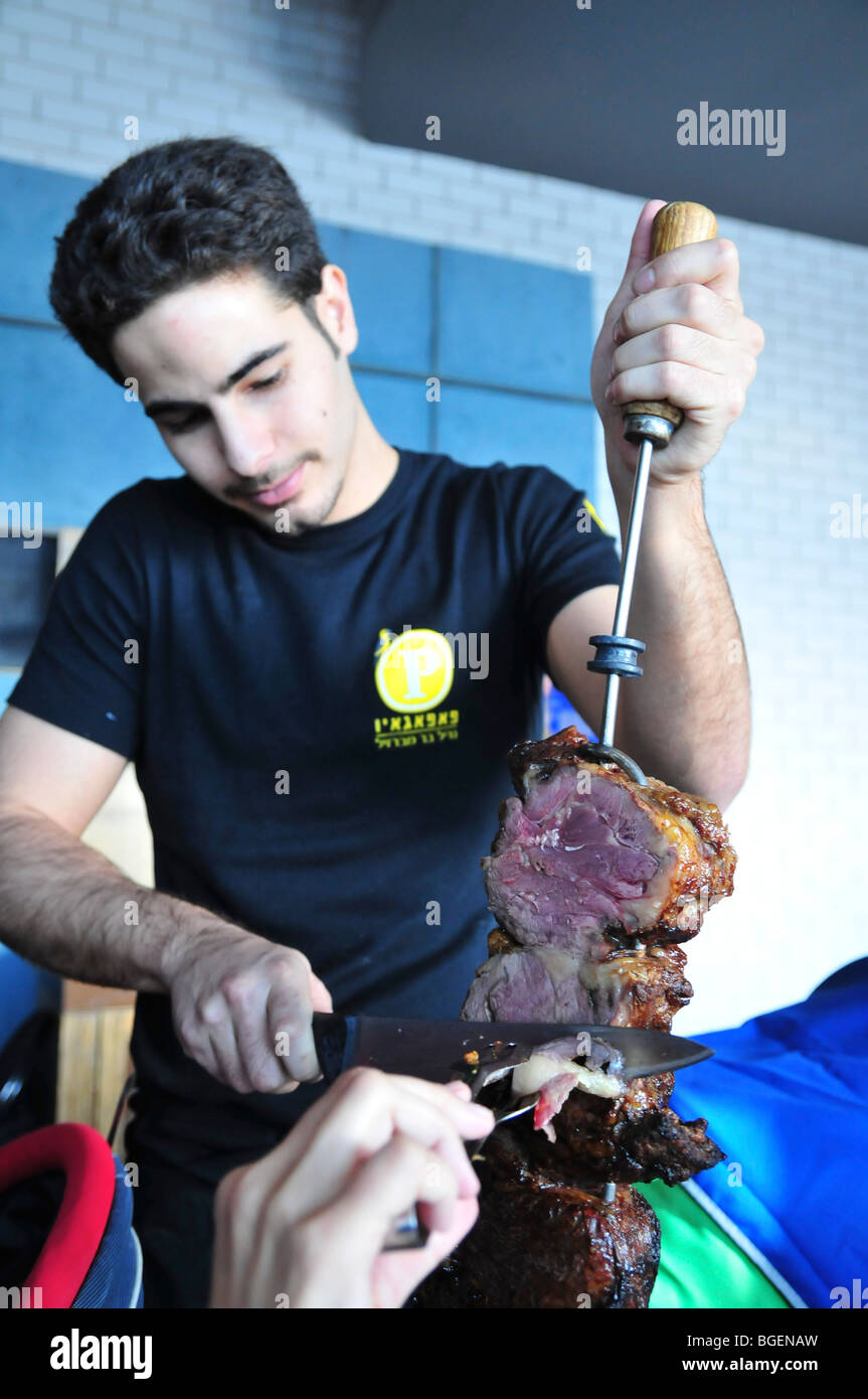 Carving Argentinian style grilled meat off a skewer Stock Photo - Alamy