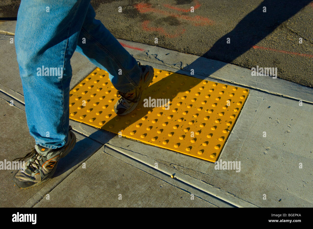 A pedestrian crosses a mobility guide tile for the visually handicapped ...