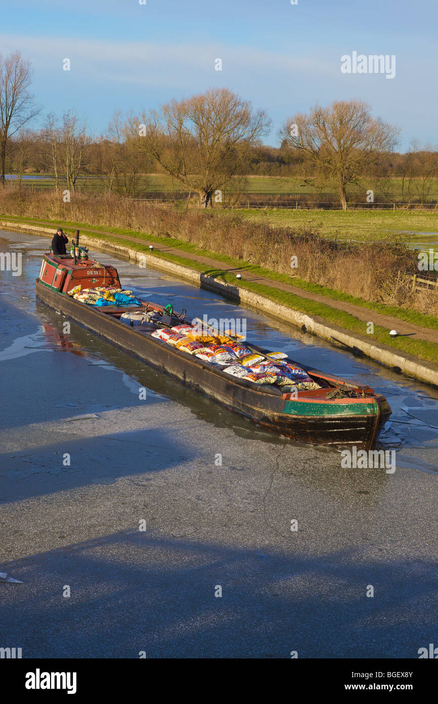 Supply barge breaking ice covered Grand Union Canal nr Stoke Hammond ...
