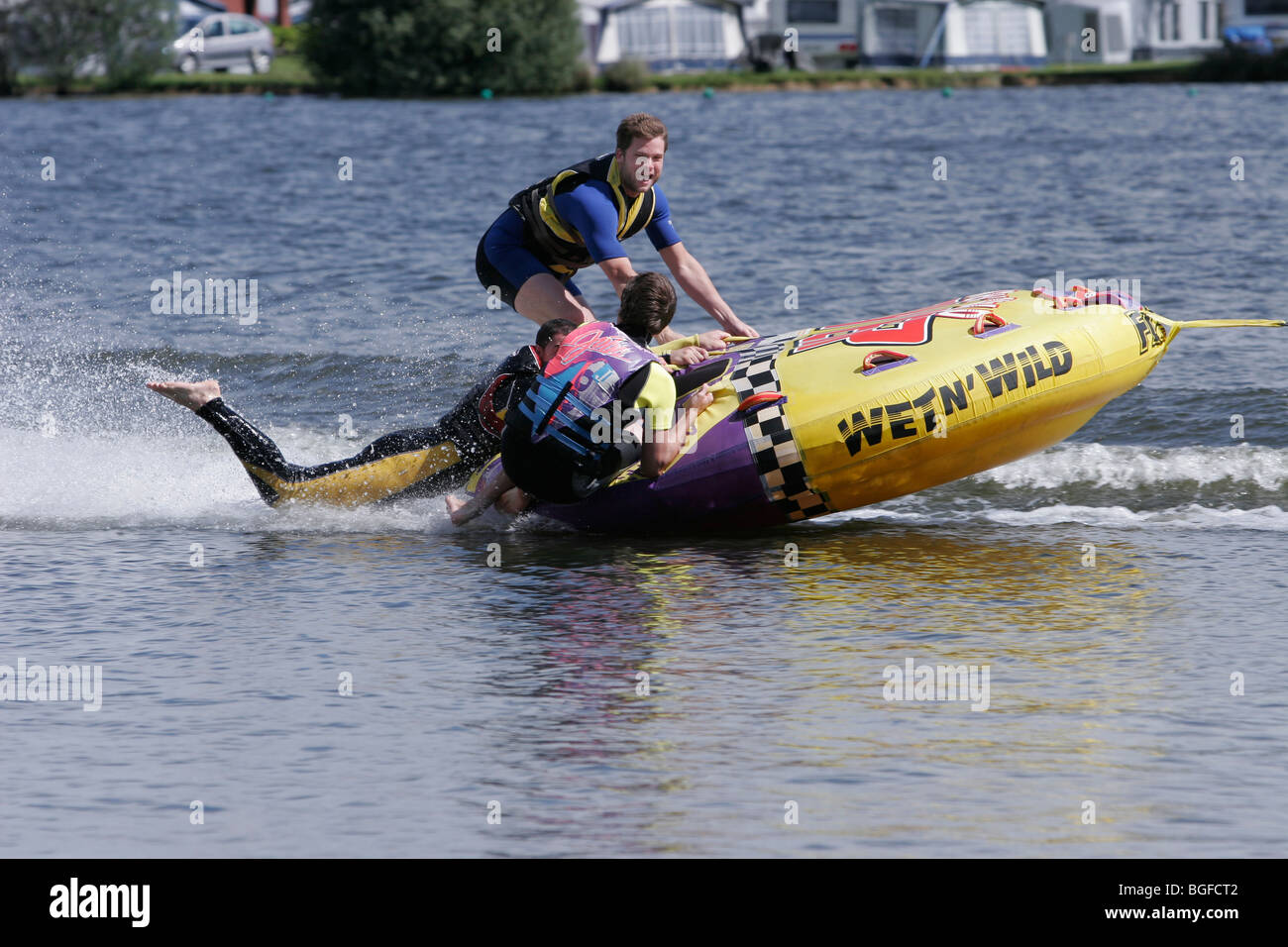 Three young males riding an inflatable being pulled by a speed boat ...