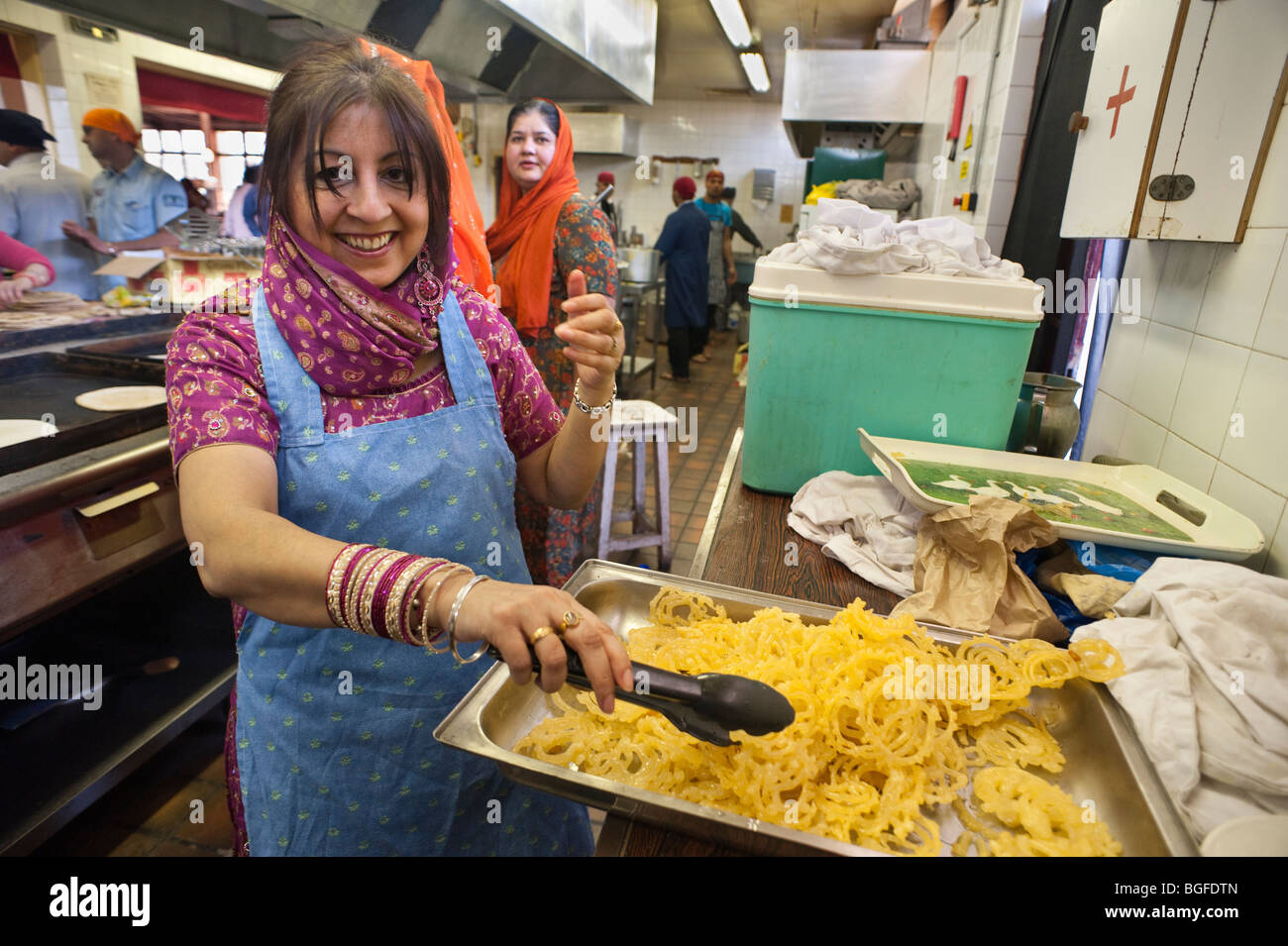 Sikh woman prepares a tray of sugary sweets in the community kitchen ...