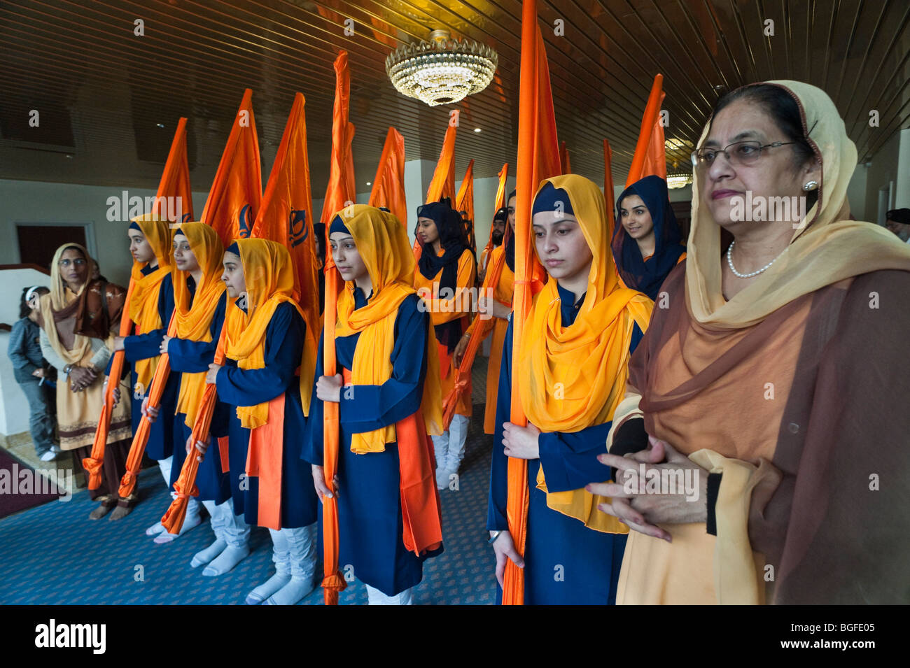 Young Sikh women in blue tunics and saffron scarfs hold Sikh Nisan ...